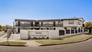 Um motel de dois andares com teto plano e varanda no andar superior.