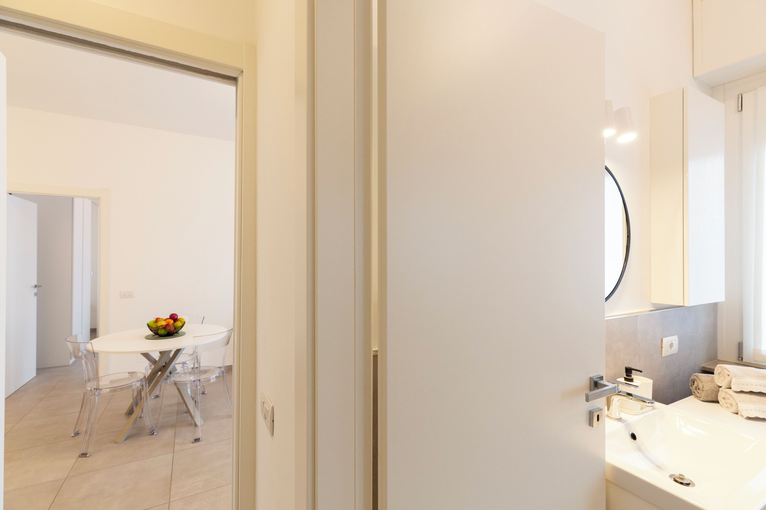 Uma casa de banho moderna com uma sanita branca, espelho e porta-toalhas.
