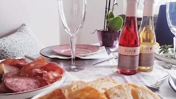 Uma mesa de jantar com pratos de comida, garrafas de vinho e um vaso de flores.
