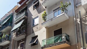 Um edifício de vários andares com varandas, uma entrada coberta e um carro estacionado em frente.