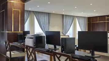 Um espaço de escritório moderno com vários postos de trabalho com computadores, cadeiras ergonômicas e uma grande janela com cortinas.