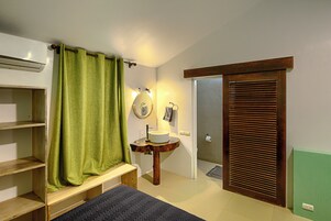 Casa de banho com toucador de madeira, cortina de chuveiro verde, espelho iluminado e porta de madeira.
