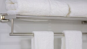 Um banheiro com um porta-toalhas com vários toalhas brancas.