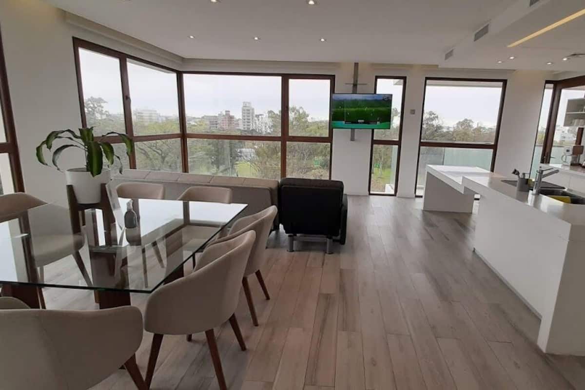 Cozinha moderna com área de jantar, janelas amplas e uma televisão de tela plana.
