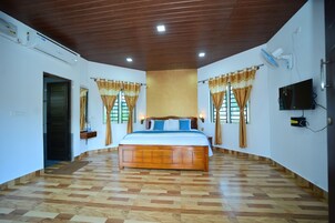 Quarto com cama de madeira, ventilador de teto, ar condicionado e televisão na parede.