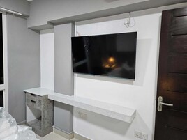 Um quarto com televisão na parede, estante embutida e uma porta.