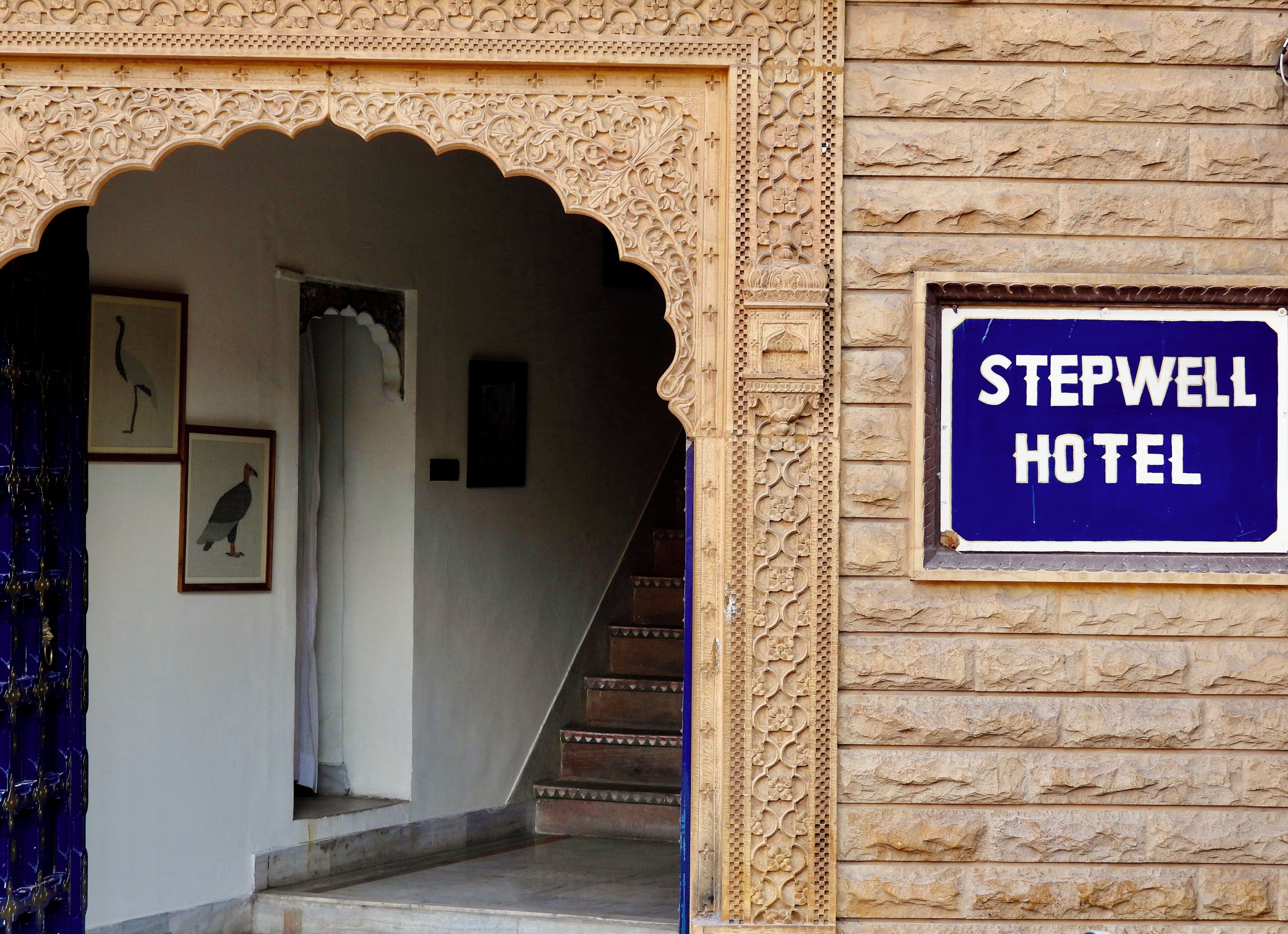 Entrada de hotel com esculturas ornamentais e uma placa com a inscrição 'Stepwell Hotel'.