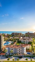 Um resort com vários edifícios, uma piscina e vista para o mar.