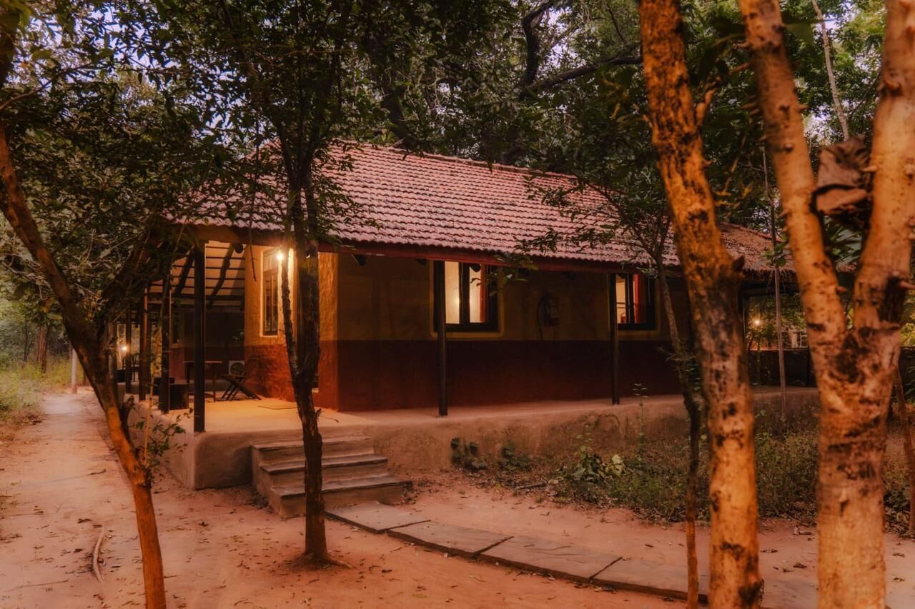 Uma cabana rústica com telhado de telhas, rodeada por árvores.