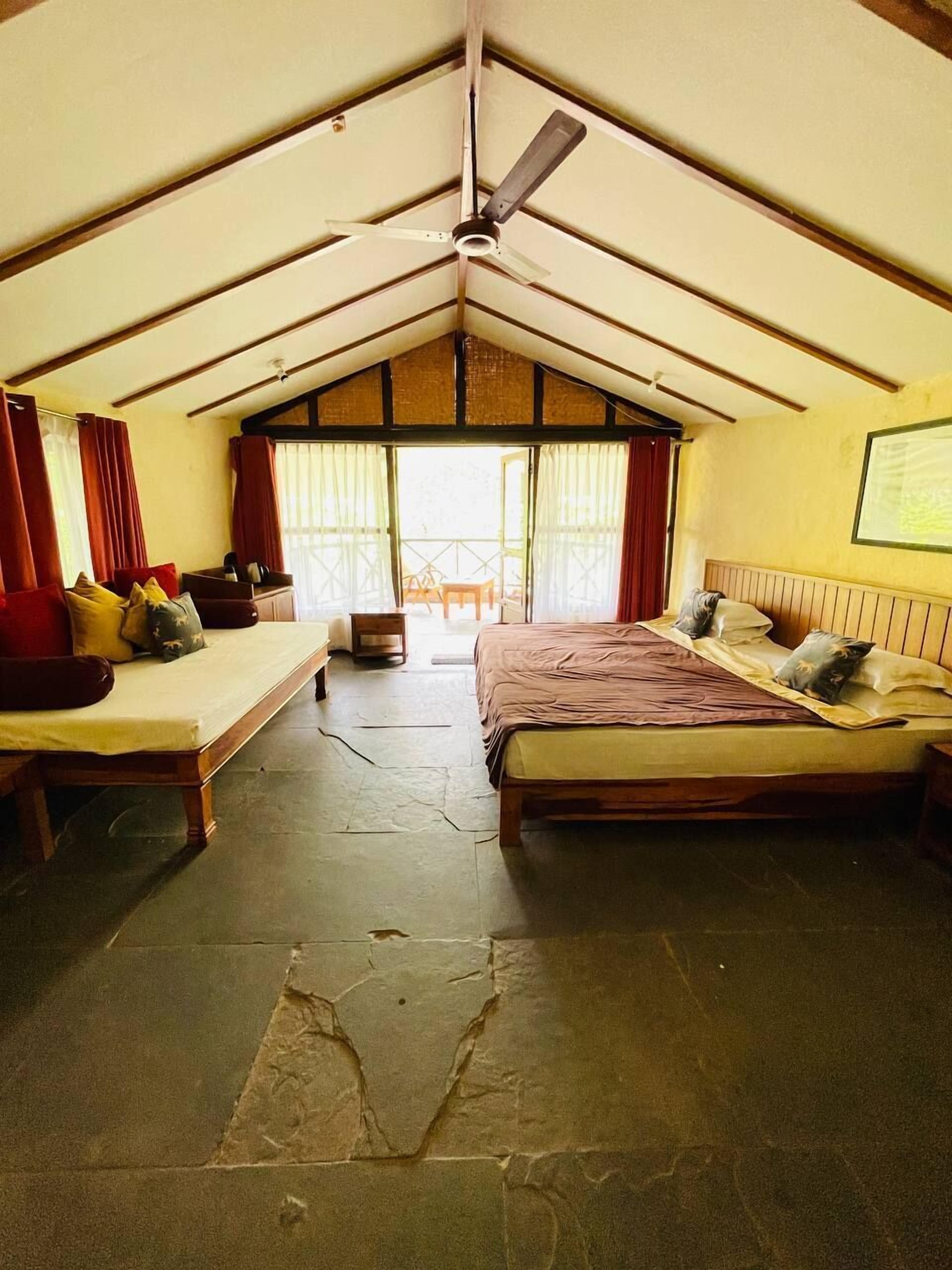 Um quarto aconchegante com teto inclinado, uma cama, um sofá e uma mesa pequena.