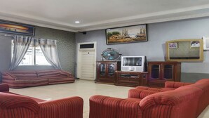 Uma sala de estar com sofá, televisão e armário.