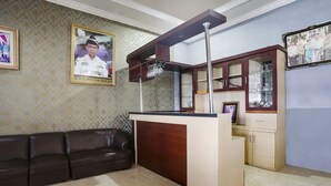 Uma área de recepção com uma mesa de madeira, um sofá de couro marrom e um armário com portas de vidro.