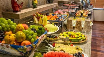 Buffet com diversas frutas e pratos.