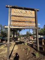 Uma placa de madeira para Casey's Midtown Cabins com informações de contato e um endereço de site.