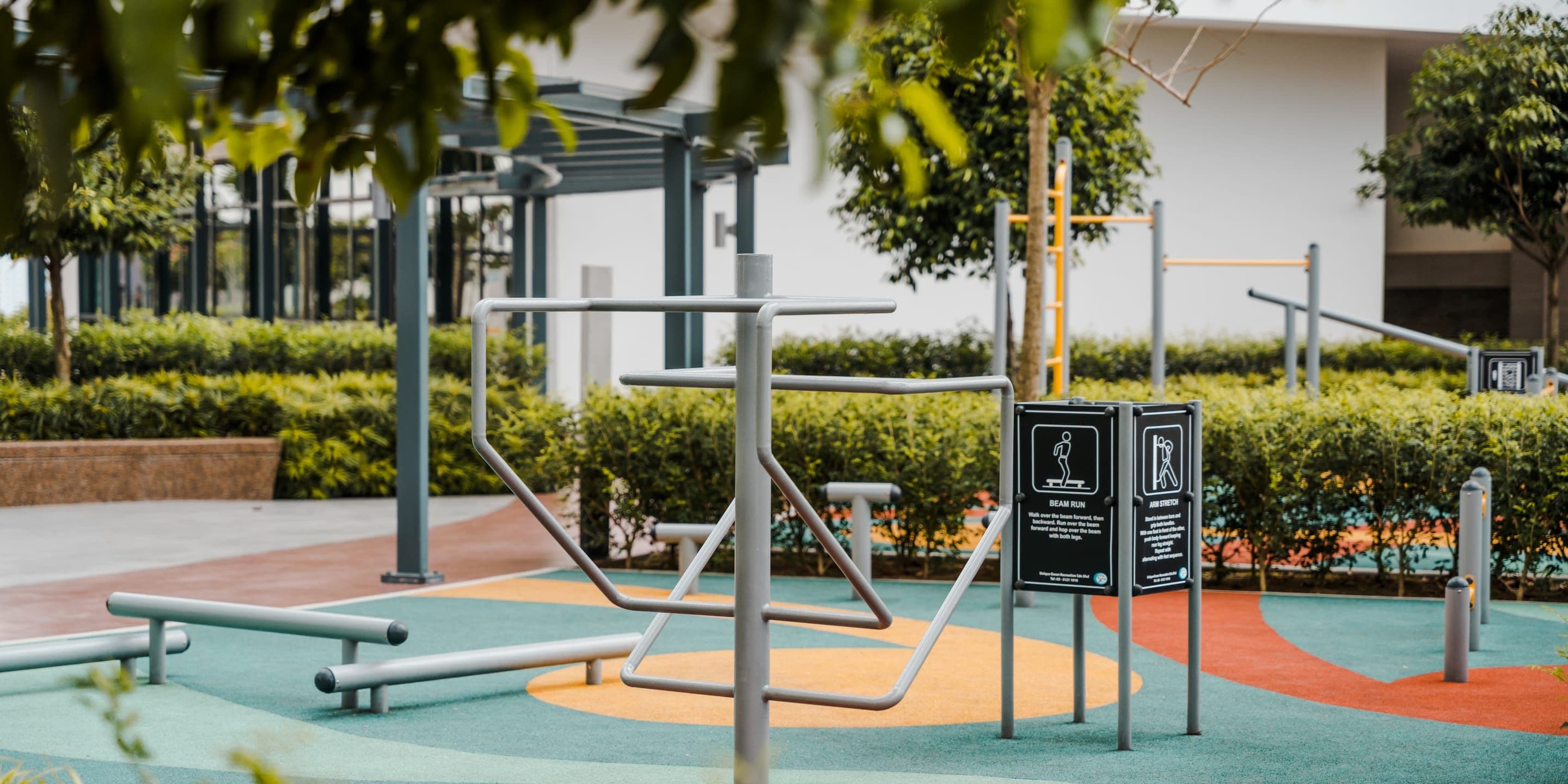 Espaço de ginástica ao ar livre com equipamentos de exercício e placas informativas.