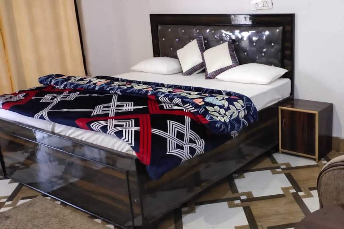 Uma cama com manta estampada, cabeceira e mesa de cabeceira.