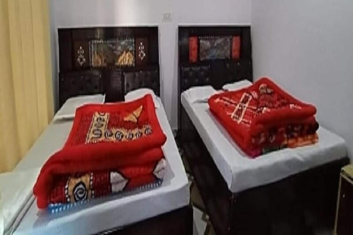 Duas camas de solteiro com cabeceiras, cada uma coberta com um cobertor vermelho.