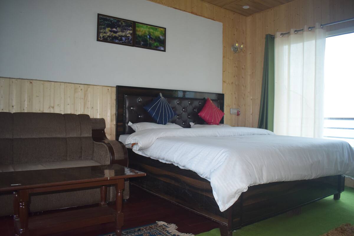 Quarto com cama, sofá e piso de madeira.