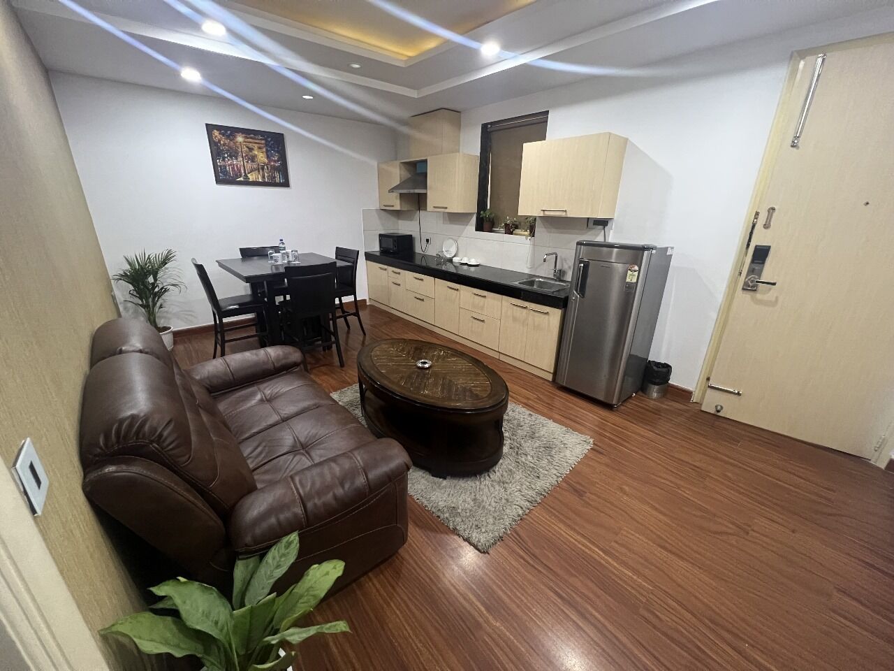 Espaço compacto com sofá, mesa de centro, mesa de jantar e cozinha, incluindo armários e geladeira.