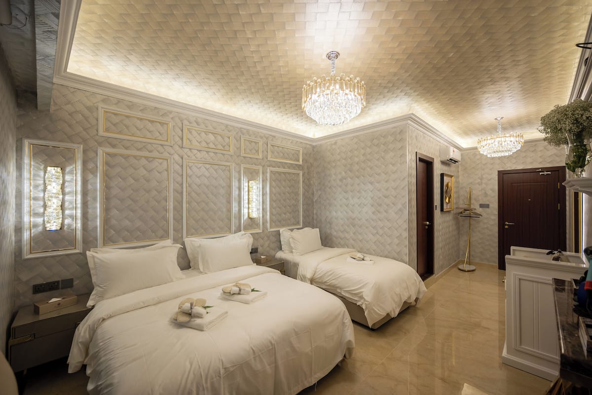 Quarto de hotel com duas camas, um candelabro e um espelho grande.