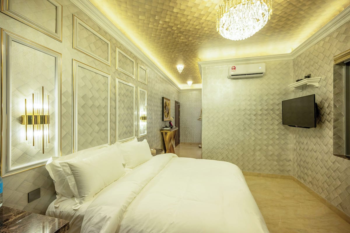 Quarto de hotel com uma cama grande, um candelabro, uma TV de tela plana e um aparelho de ar condicionado.
