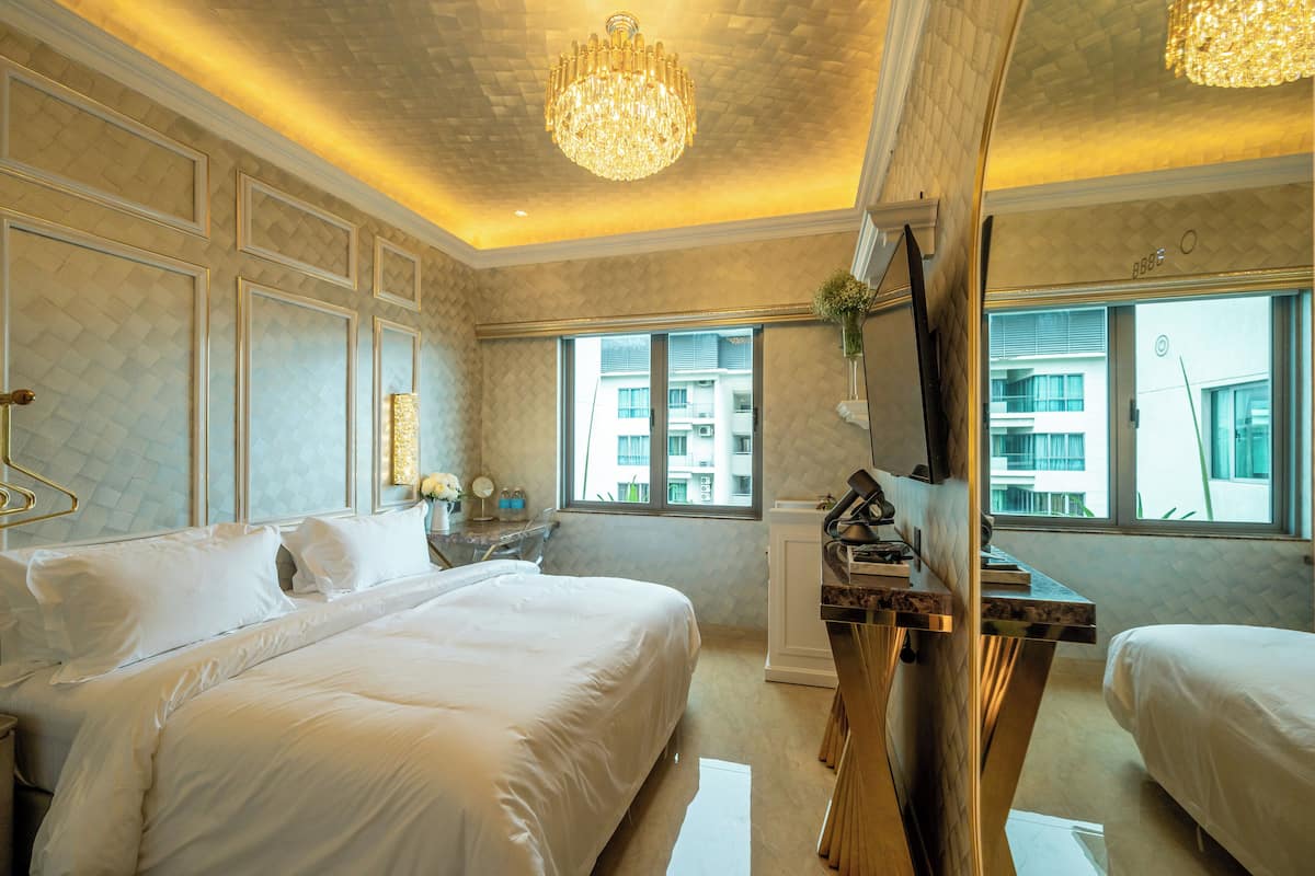 Quarto de hotel com uma cama grande, uma escrivaninha com espelho e vista para a cidade pela janela.