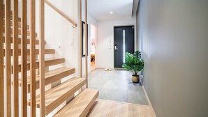 Um interior moderno com uma escada de madeira, um vaso de planta e uma porta que dá para outro quarto.