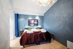 Um quarto com uma cama, uma mesa de cabeceira, um quadro e um lustre.