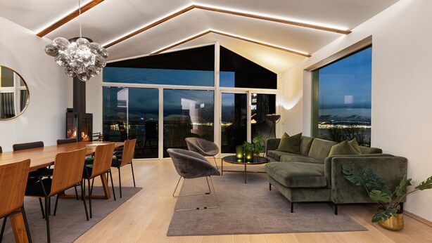 Uma sala de estar moderna com área de jantar, janelas amplas e vista para a cidade.