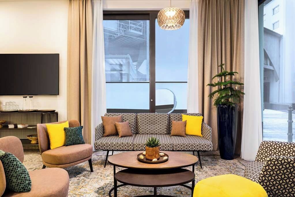 Uma sala de estar moderna com um sofá, poltronas, uma mesa de centro e uma televisão.