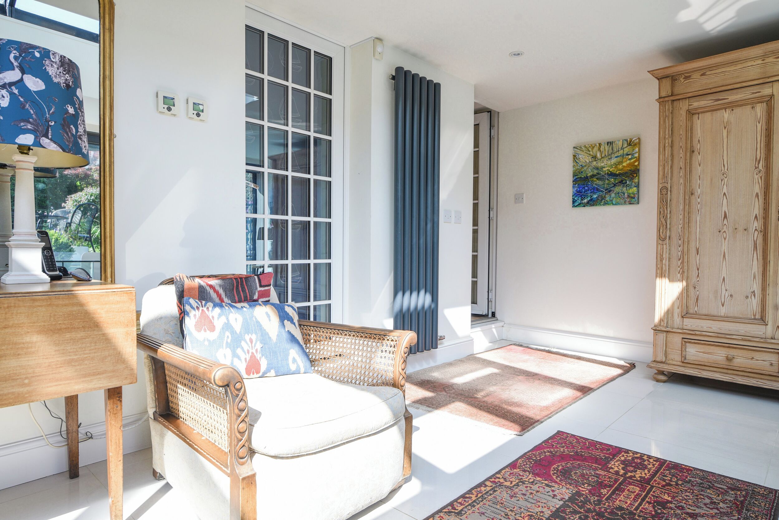 Um quarto com um sofá branco, um armário de madeira e uma janela grande com persianas.