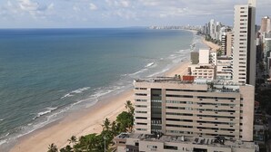 Paisagem costeira com praia, edifícios altos e céu claro.