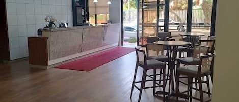 Um amplo espaço de recepção com balcão, área de estar e grandes janelas que oferecem vista para o exterior.