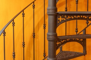 Uma escadaria de metal com balaústres decorados e corrimão.