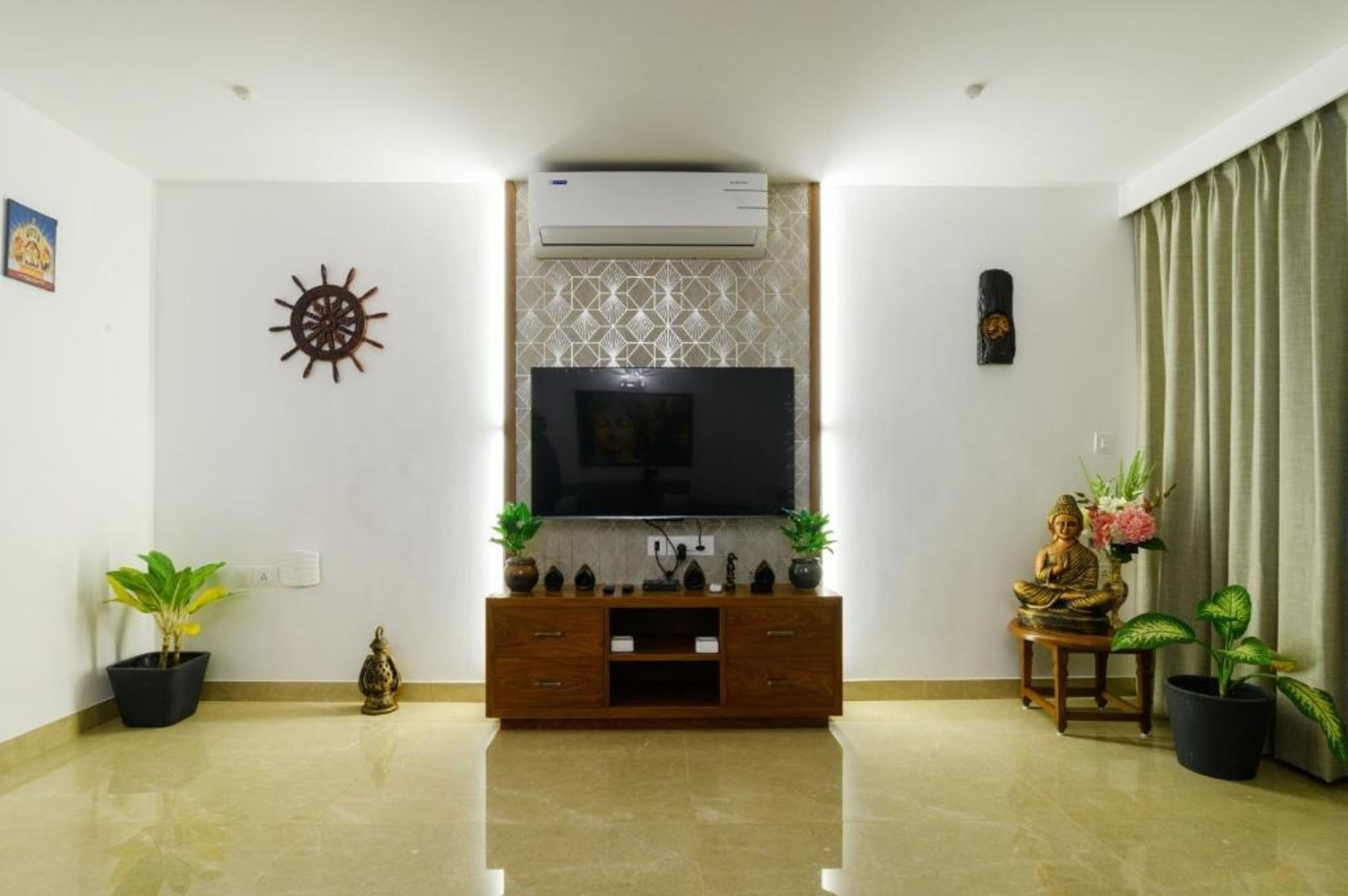 Sala de estar com televisão de tela plana, móvel para sistema de som em madeira, vasos de plantas e objetos decorativos.