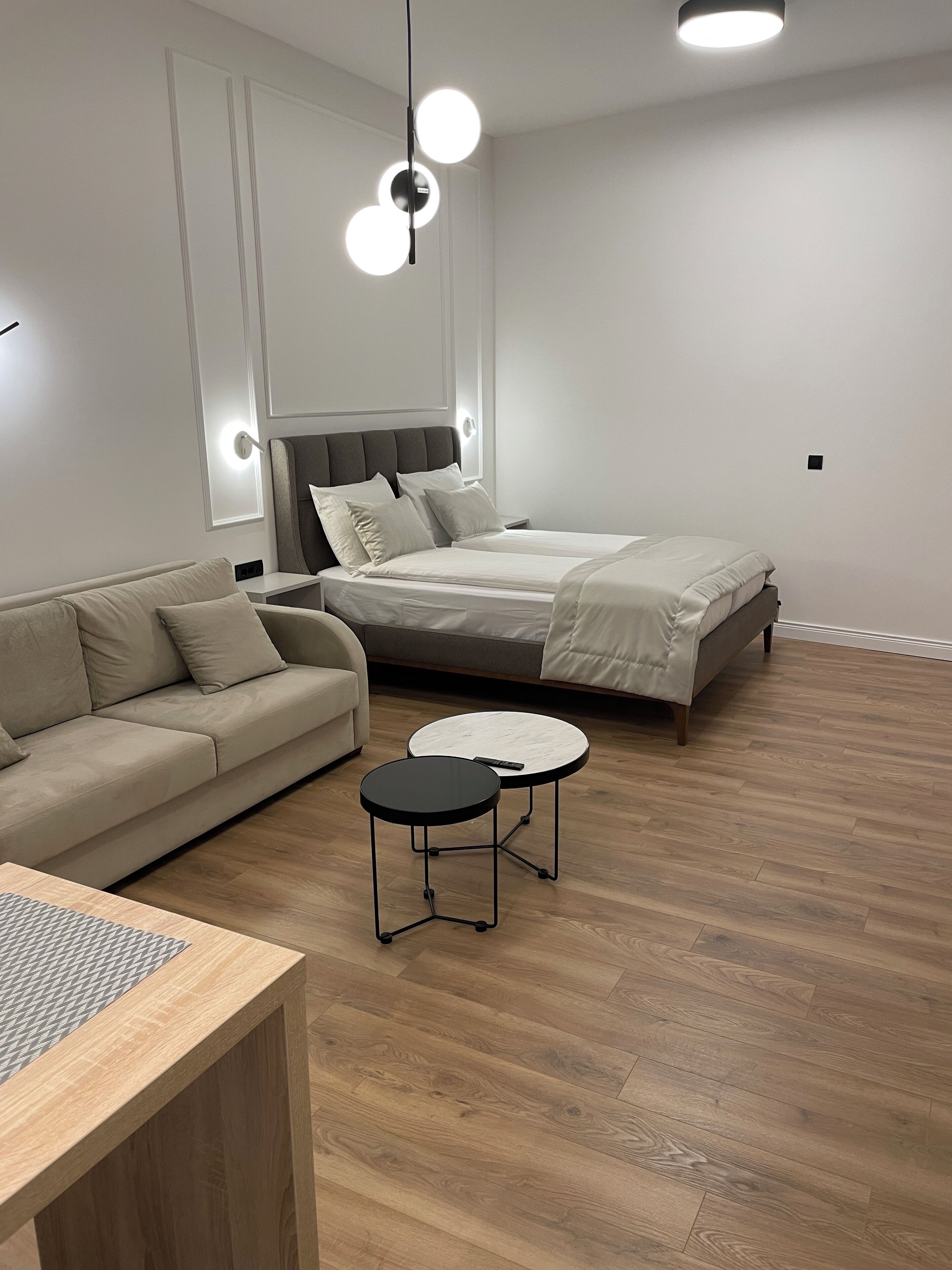 Quarto moderno com cama, sofá e uma pequena mesa redonda.
