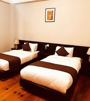 Quarto de hotel com duas camas, piso de madeira e uma moldura com quadro na parede.