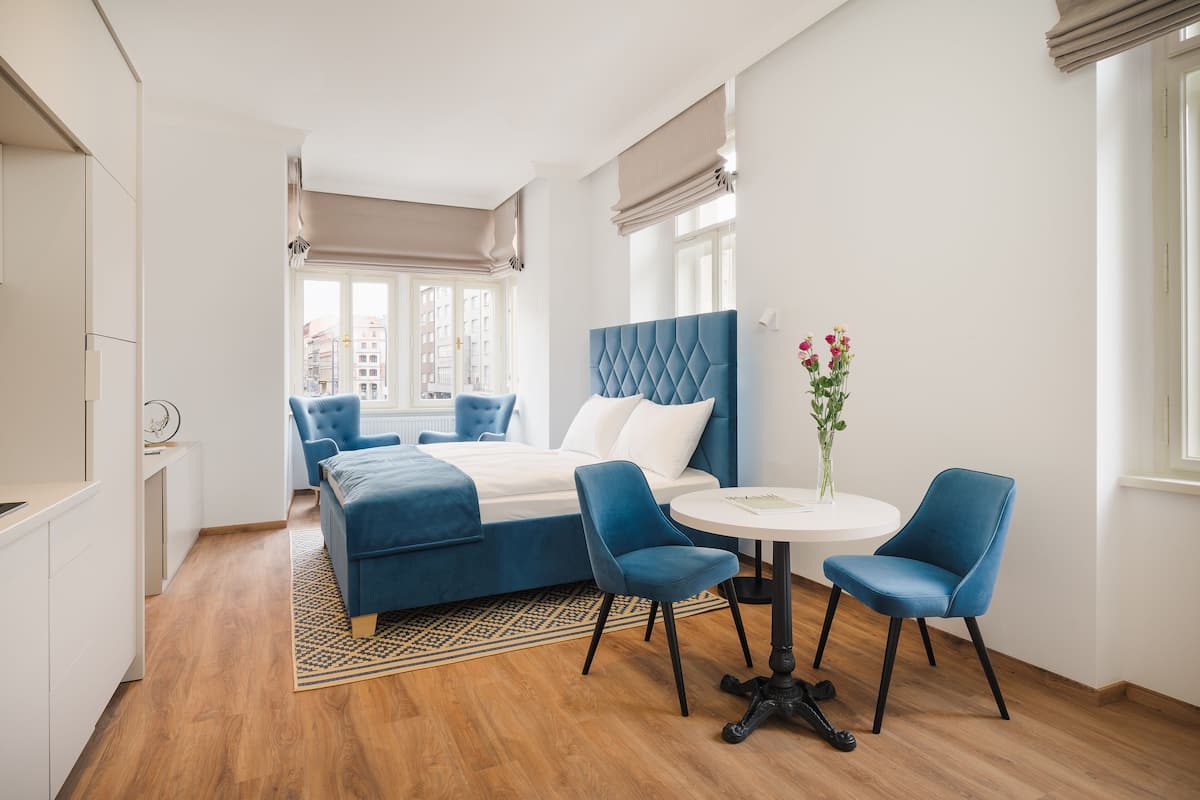 Um quarto moderno com uma cama grande, uma mesa de jantar redonda e cadeiras azuis.