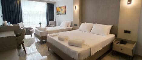 Quarto de hotel moderno com uma cama grande, uma cama menor, uma escrivaninha e uma cadeira.