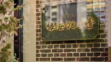 Pared de tijolos com uma placa que diz "洋食屋" e "豊登ブランコ".