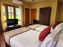 Quarto de hotel com duas camas, televisão, escrivaninha e guarda-roupa.