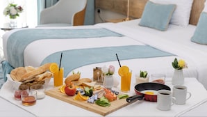 Uma bandeja de café da manhã com pão, frutas, uma frigideira e bebidas sobre a cama.