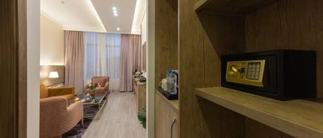 Uma sala de estar moderna com um sofá, poltronas, uma mesa de centro e um abajur. Há um armário de madeira com um cofre em cima.