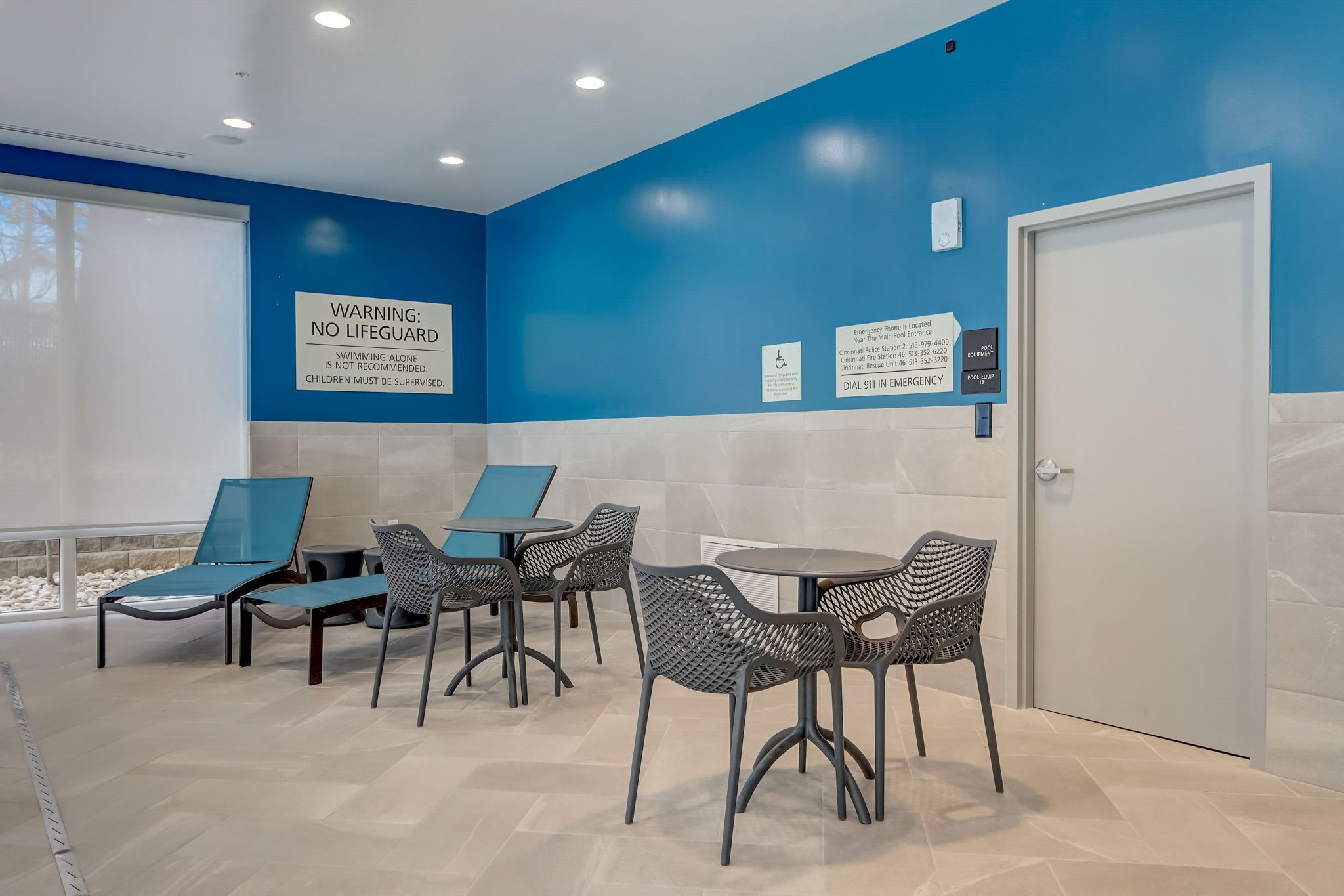 Área da piscina com espreguiçadeiras, uma mesa e uma porta. Um aviso recomenda não nadar sozinho e supervisão para crianças.