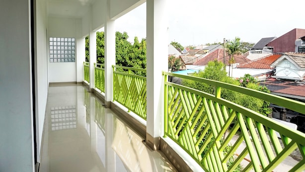 Uma varanda com guarda-corrimão verde, piso de azulejos e vista para casas vizinhas.