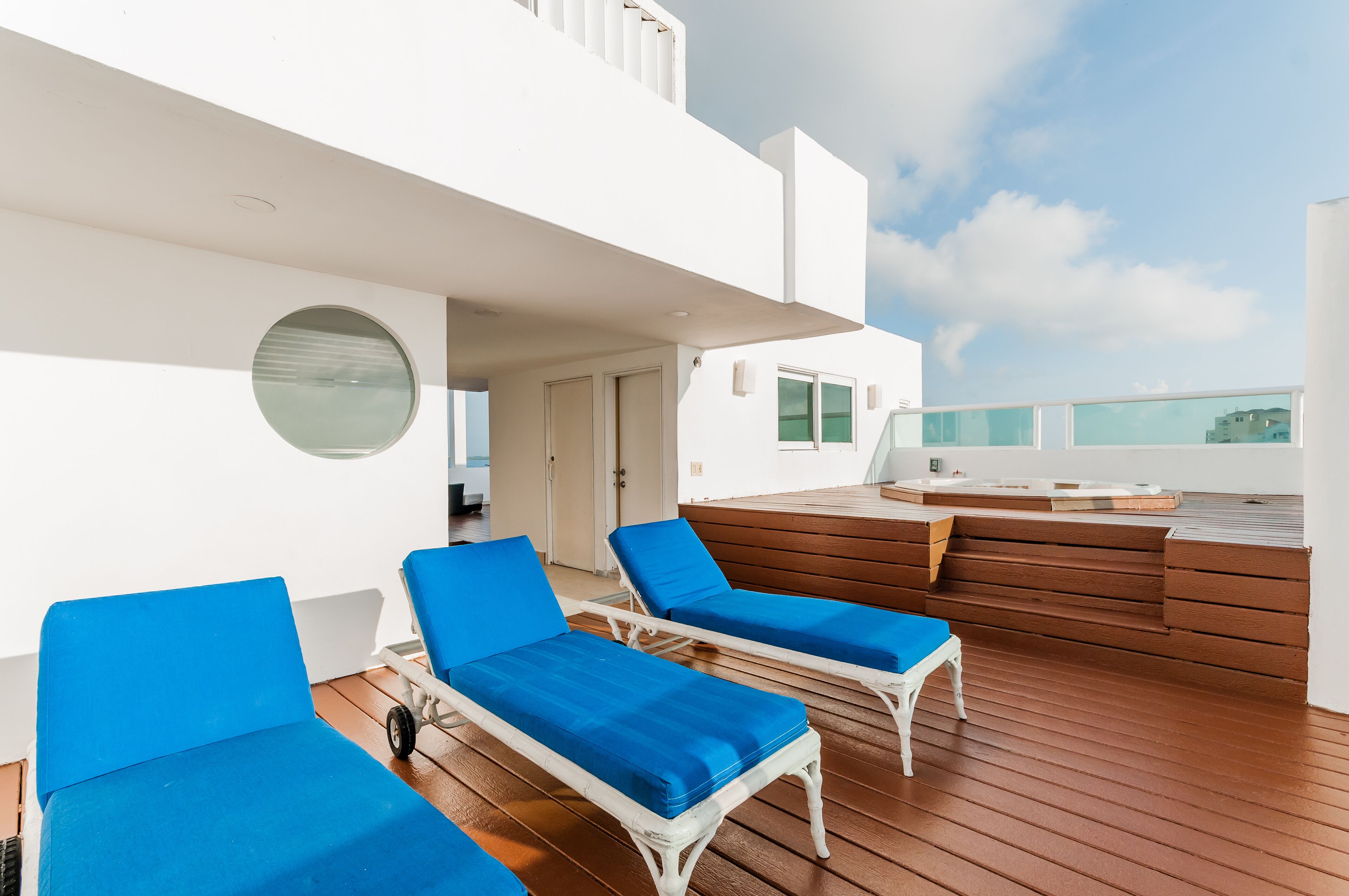 Um deck com espreguiçadeiras azuis e piso de madeira.