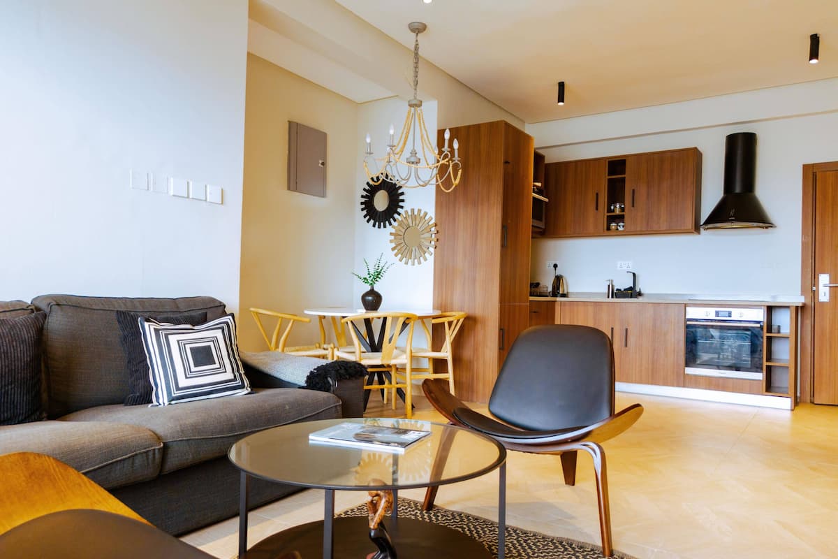 Uma sala de estar moderna com um sofá, uma mesa de centro e um espaço de jantar com cadeiras e uma pequena mesa.