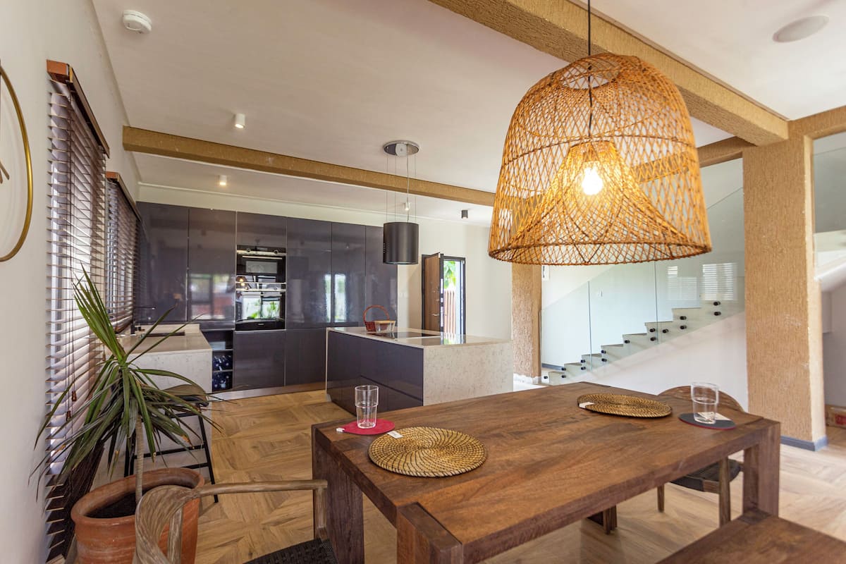 Uma cozinha moderna com armários escuros, uma ilha central e um pendente de fibra natural.
