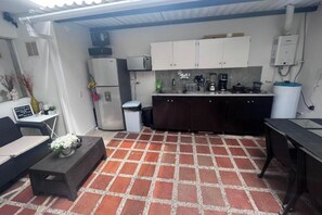 Cozinha compacta com armários brancos, geladeira, cafeteira e aquecedor de água.