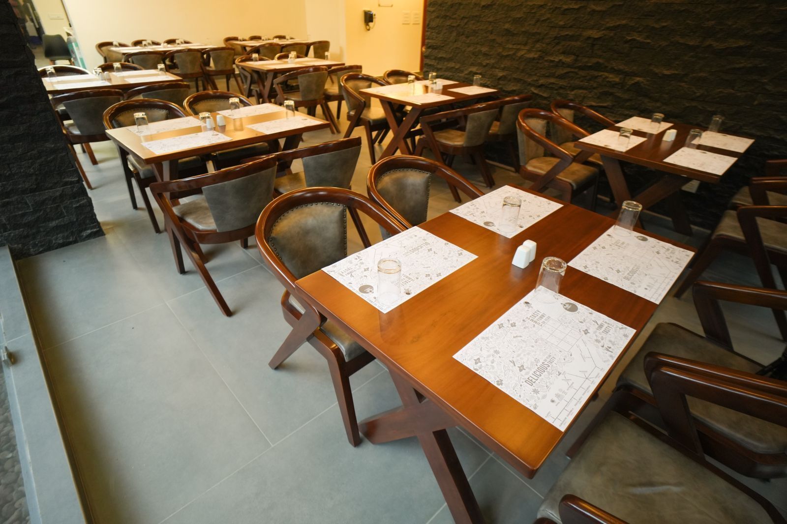 Uma sala de conferências com mesas e cadeiras de madeira, cada uma com um menu sobre a mesa.